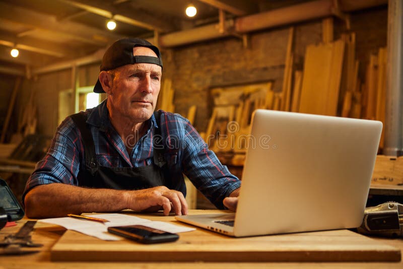 Senior Carpenter Works on the Computer in the Workshop Stock Photo ...