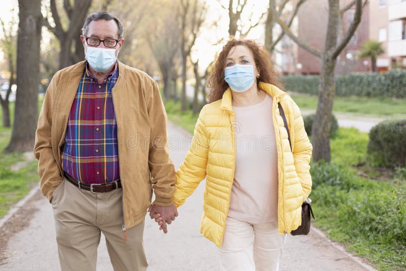 Senior Caucasian Couple Walking In The Park Holding Hands Both Are
