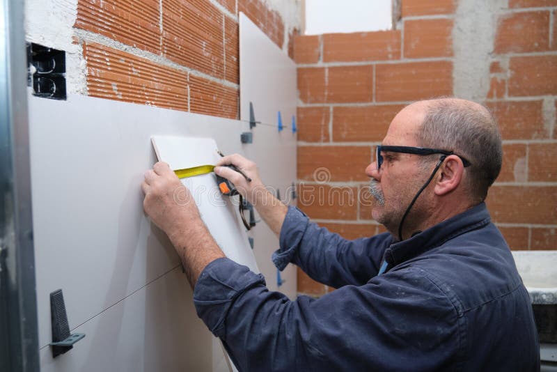 Senior Constructor Worker Adjusting White Ceramic Tiles on the Wall ...