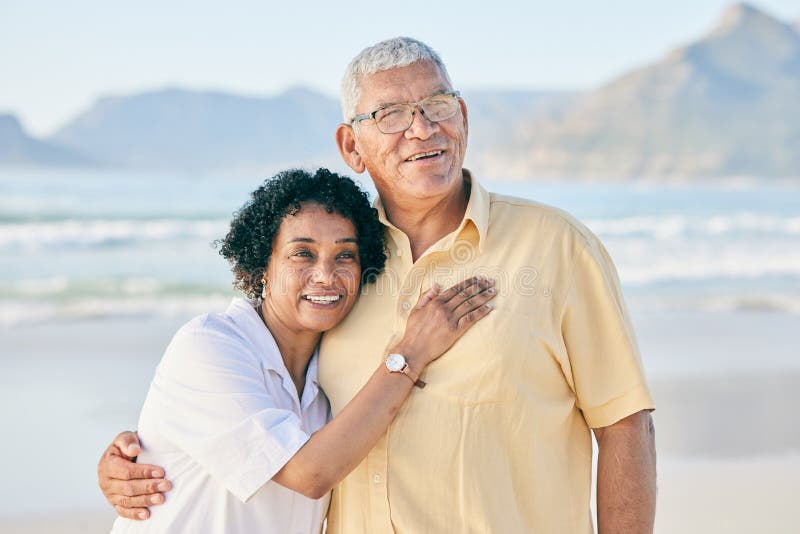 Senior Couple At Beach Hug And Smile With Travel Retirement And Love