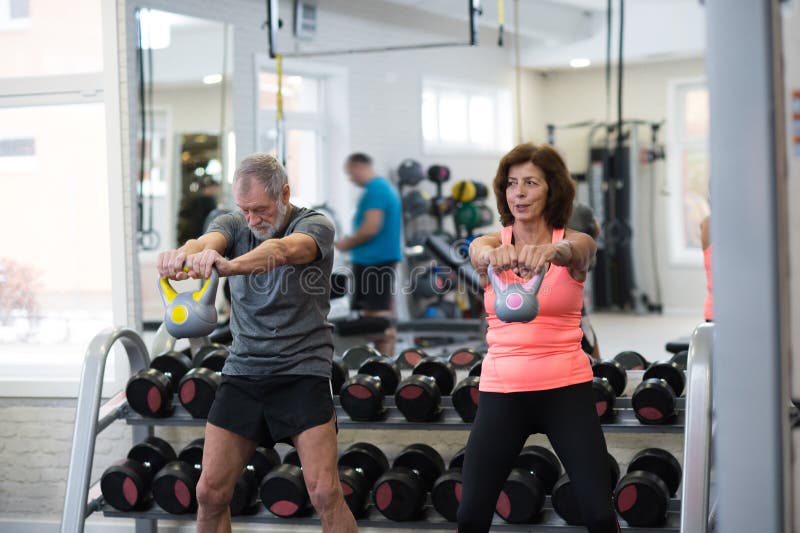 Senior Couple in Gym Working Out Using Kettlebells. Stock Photo - Image ...