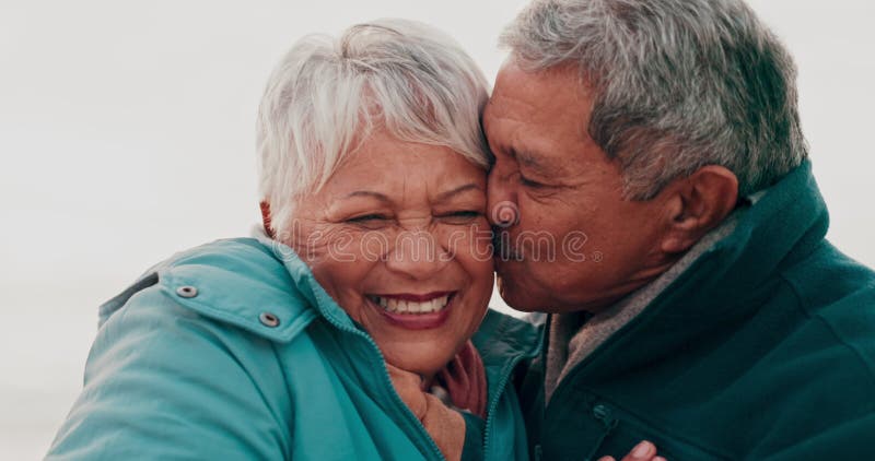 Senior Couple Hug And Face On Sofa With Kiss On Cheek For Funny Memory
