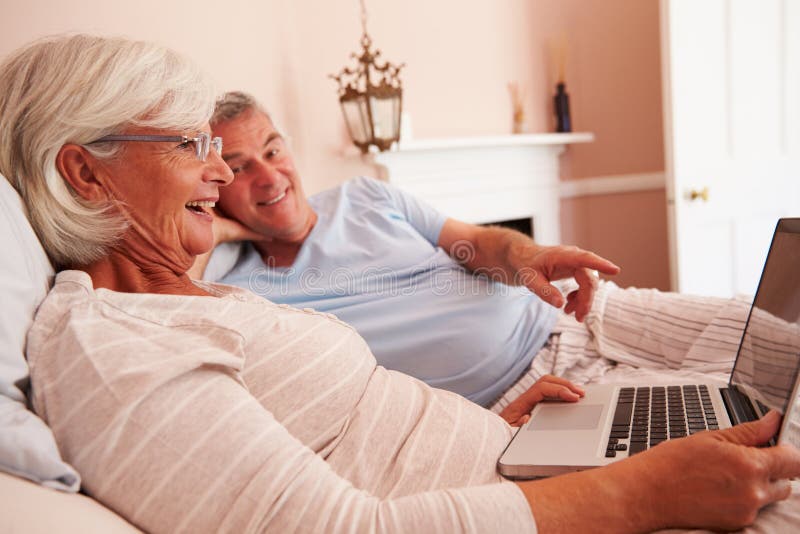 Senior Couple Lying in Bed Looking at Laptop Computer Stock Photo ...