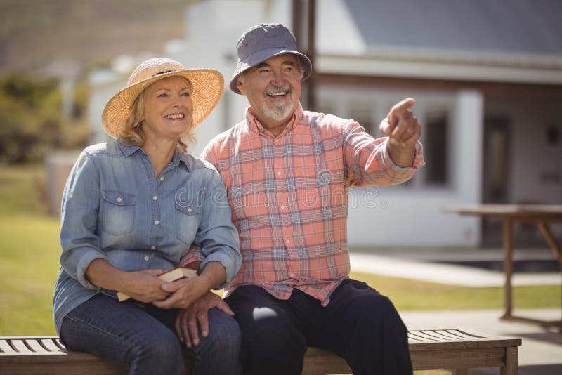 Senior Couple Pointing at View while Sitting on Bench Stock Image ...