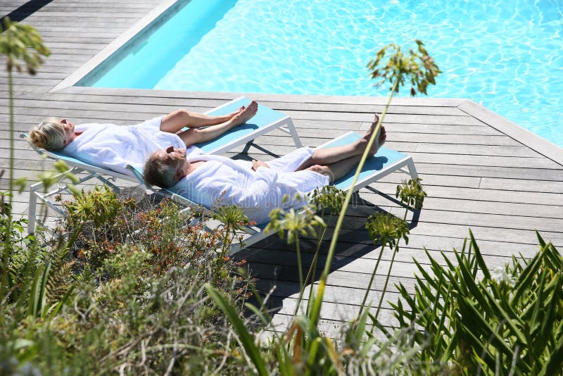 Senior Couple Relaxing by Swimming Pool Stock Photo - Image of serenity ...