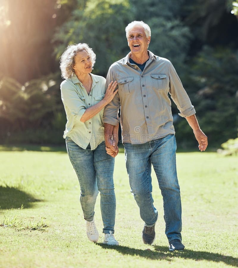 Senior Couple Walking In Park Garden And Sunshine To Relax Wellness