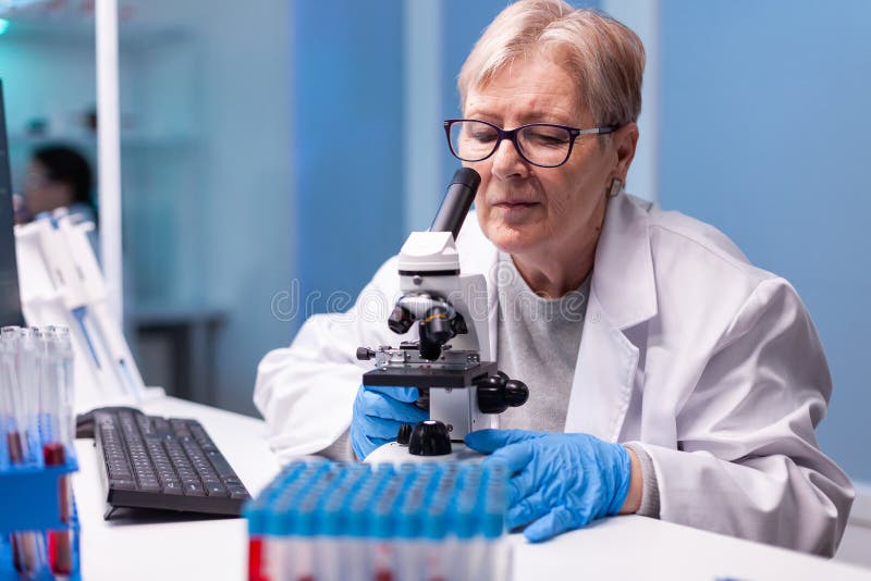 Senior Doctor in White Coat Looking into Microscope in Laboratory ...