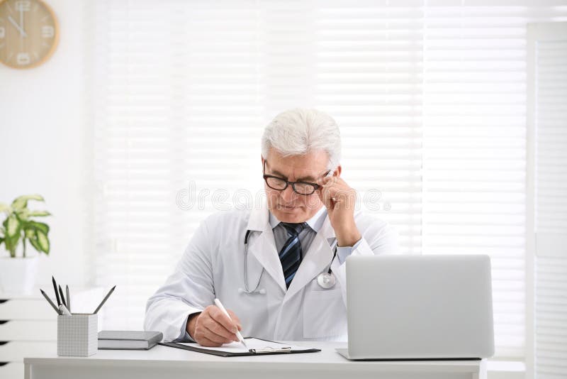 Senior Doctor Working at Table Stock Photo - Image of person, doctor ...