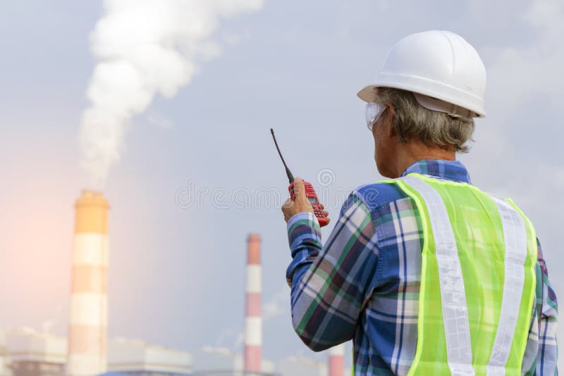 A Senior Electrical Engineer Wearing a Helmet Uses a Walkie-talkie ...
