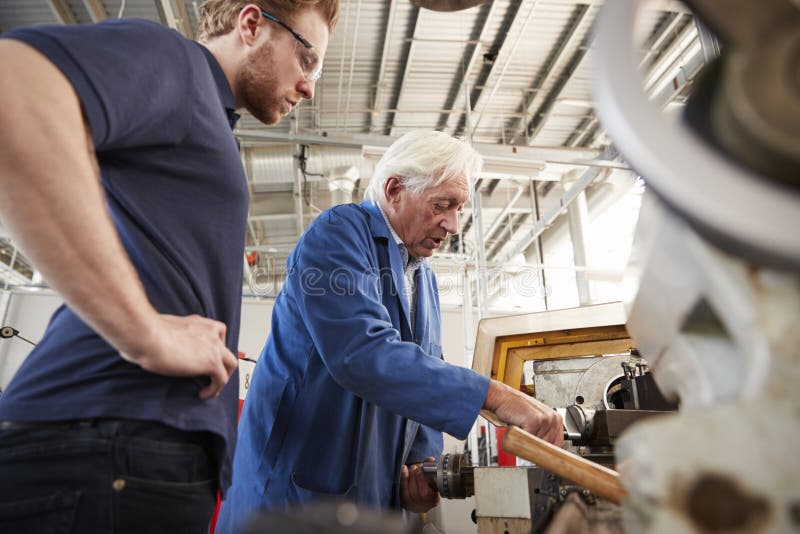Senior Engineer Demonstrating Equipment To Apprentice at Machine Bench ...