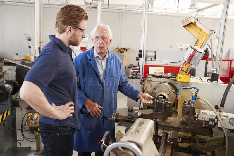 Senior Engineer Talking To Apprentice at Machine Bench Stock Photo ...