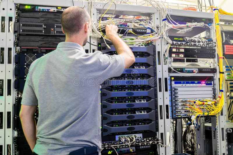 Senior Engineer Works Near the Racks with Server Equipment. the Man is ...