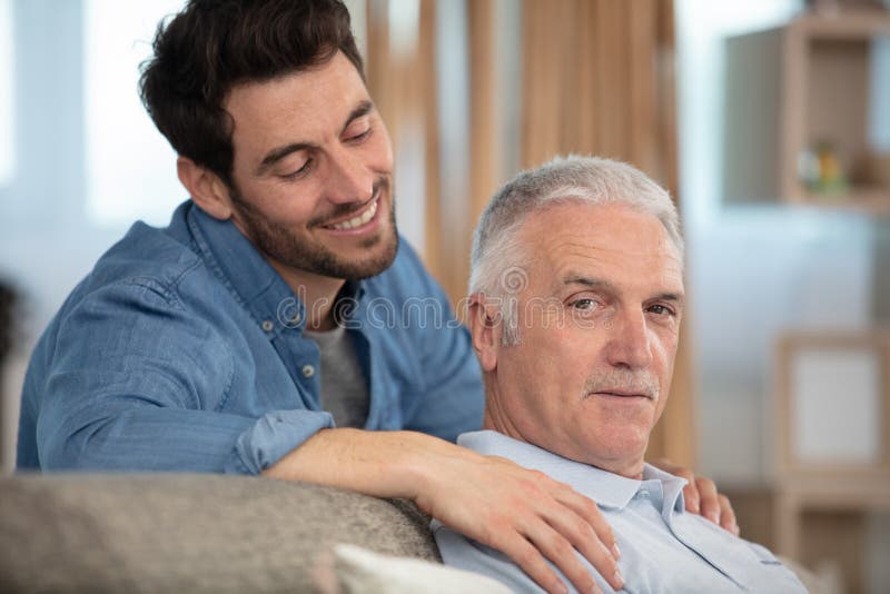 Senior Father With Adult Son Relaxing On Sofa At Home Stock Image