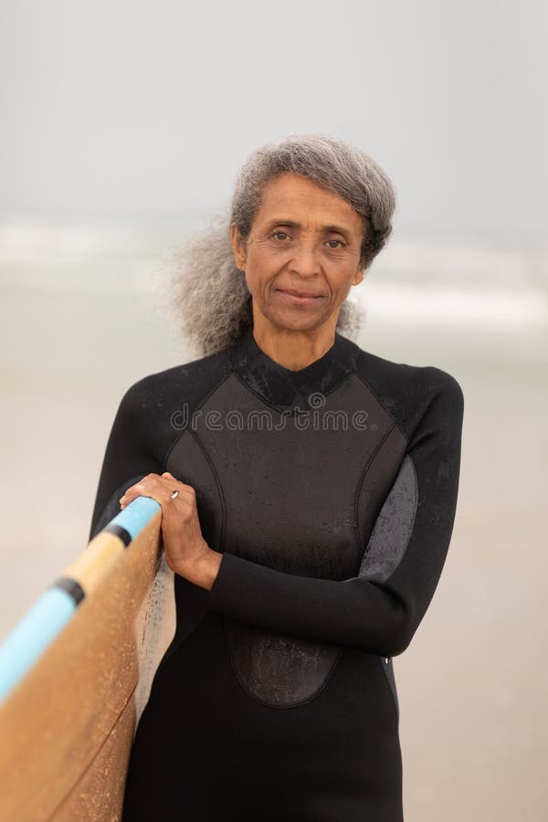 Senior Female Surfer Standing with Surfboard and Looking at Camera on ...