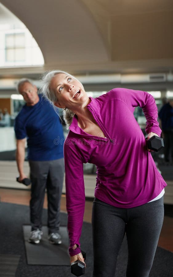 Senior Fitness Dumbbells And People Stretching At Gym For Training