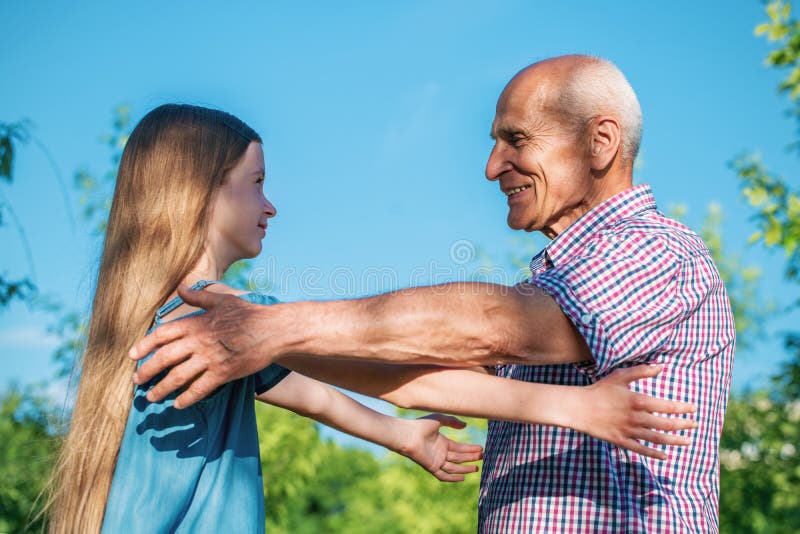 Senior Grandpa And Young Granddaughter Hugging At City Park Stock