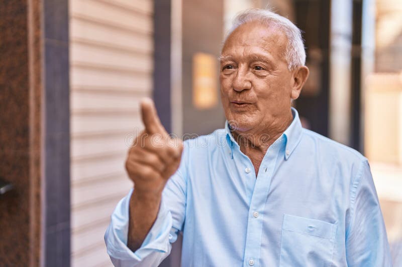 Senior Grey-haired Man Smiling Confident Pointing with Finger at Street ...