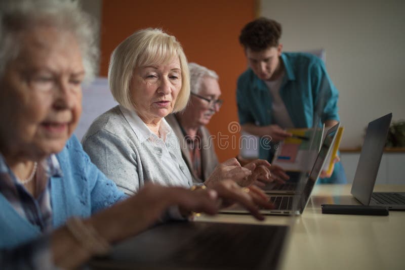 Senior Group With Young Instructor Learning Together In Computer Class