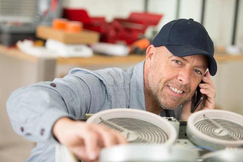 Senior Handyman Taking Smartphone Call while Working on Appliance Stock ...