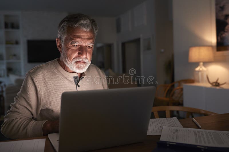 Senior Hispanic Man Checking His Finances Online at Home Using a Laptop ...