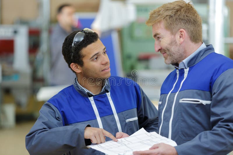 Senior and Junior Male Workers Looking at Plans in Workshop Stock Photo ...