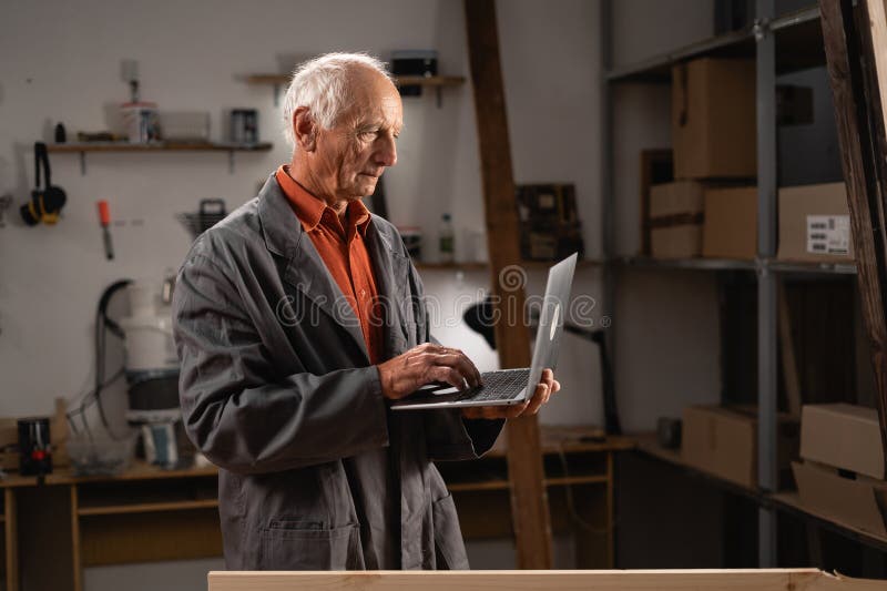 Senior Male Carpenter Using Laptop Computer Working His Workshop. Stock ...
