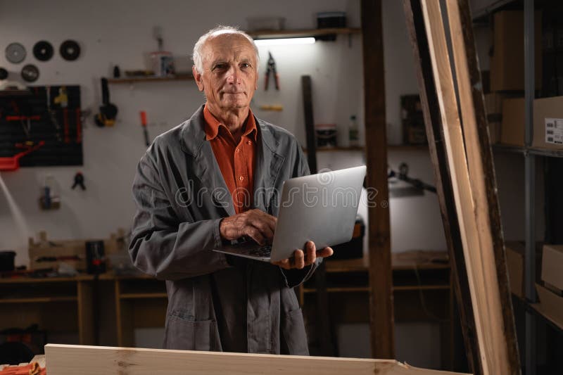 Senior Male Carpenter Using Laptop Computer Working His Workshop. Stock ...