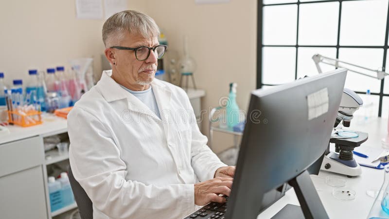 A Senior Male Scientist Analyzes Data on a Computer in a Modern ...