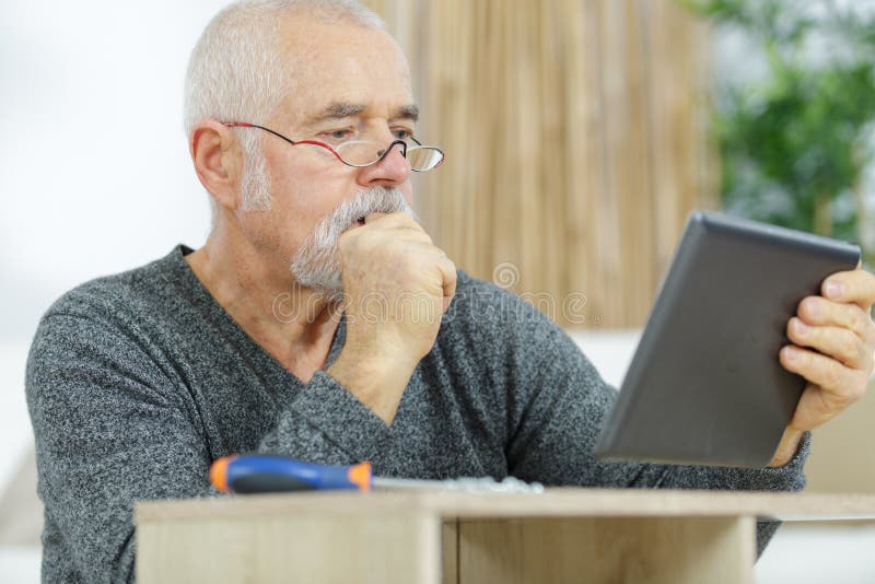 Senior Man Checking Manual on Tablet Stock Photo - Image of creativity ...