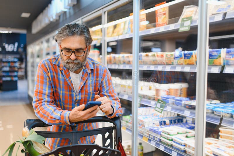 Senior Man Doing Grocery Shopping at the Supermarket, he is Using Apps ...