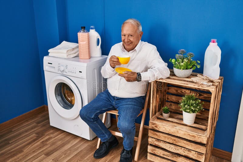 Senior Man Drinking Coffee Waiting for Washing Machine at Laundry Room ...
