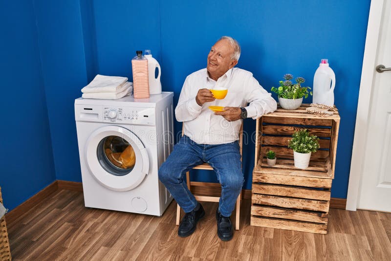 Senior Man Drinking Coffee Waiting for Washing Machine at Laundry Room ...
