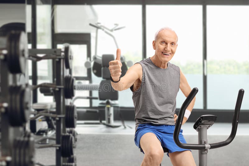 Senior Man on an Exercise Bike Looking at the Camera and Gesturing ...