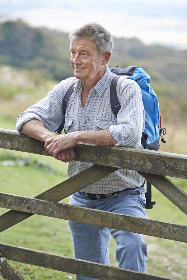Senior Man Hiking in Countryside Resting by Gate Stock Photo - Image of ...