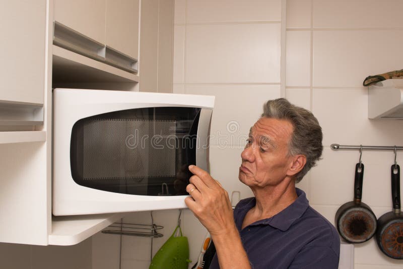 Senior Man in His Kitchen Looking into His Microwave Stock Photo ...