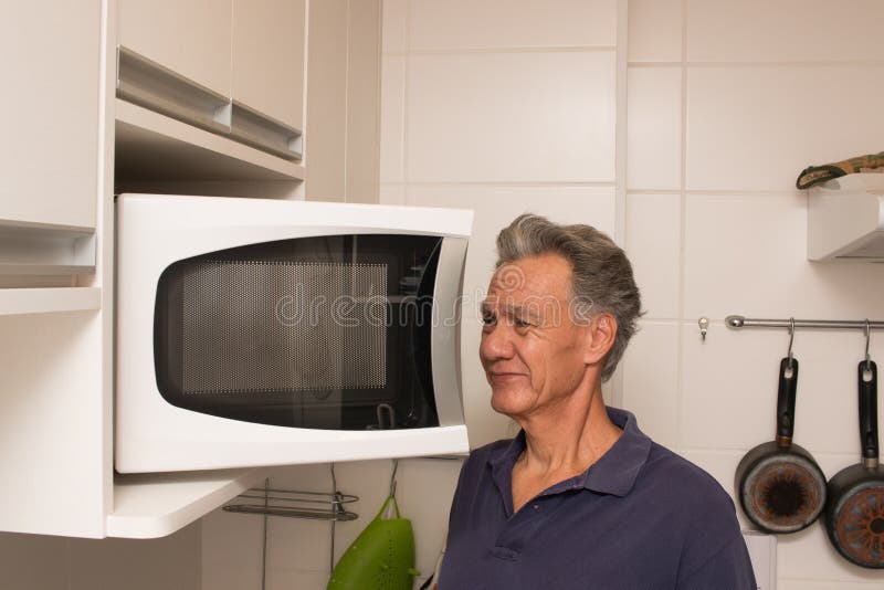 Senior Man in His Kitchen Looking into His Microwave Stock Image ...