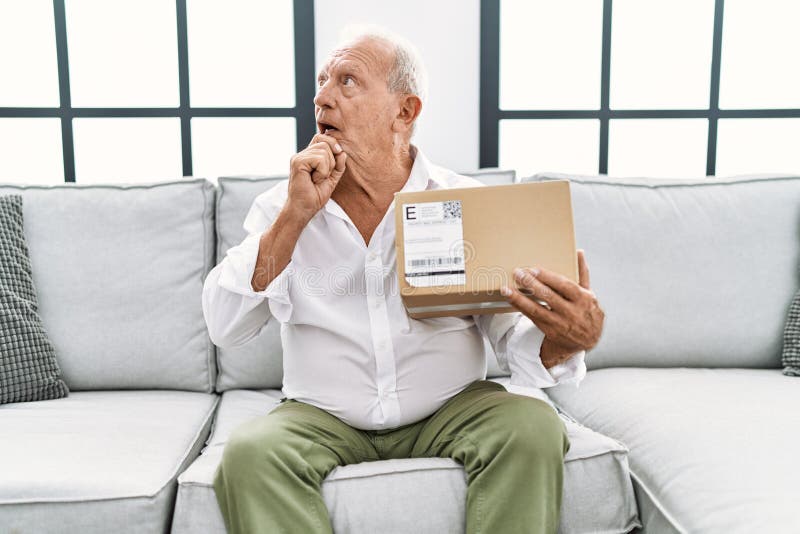 Senior Man Holding Delivery Package at Home Serious Face Thinking about ...
