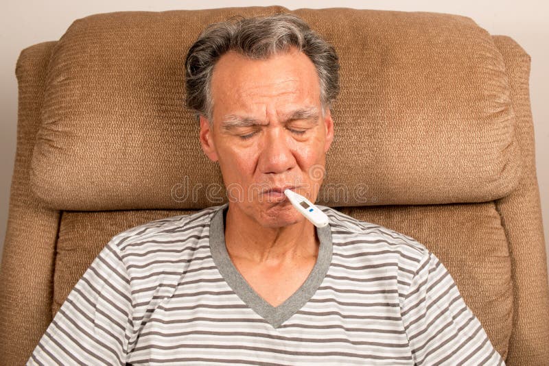 Man At Home Checking His Temperature On A Digital Thermometer Stock