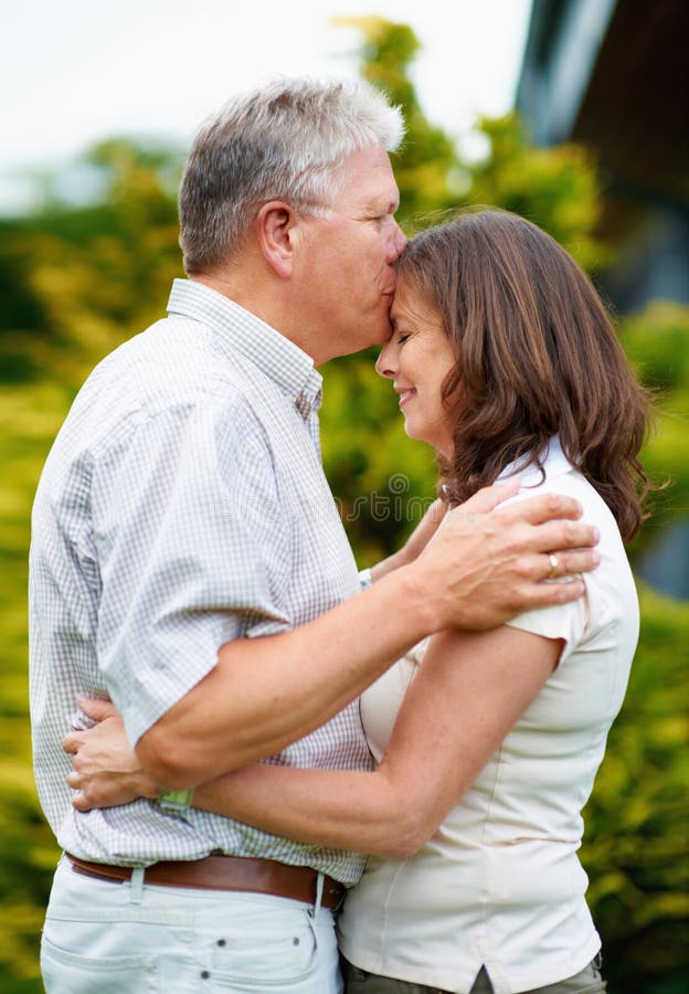 Senior Man Kissing And Woman On Forehead In Backyard Care Or Couple
