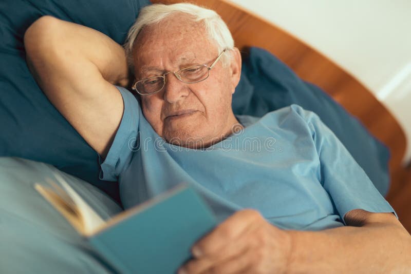 Senior Man Lying on Bad and Reading Book Stock Photo - Image of male ...