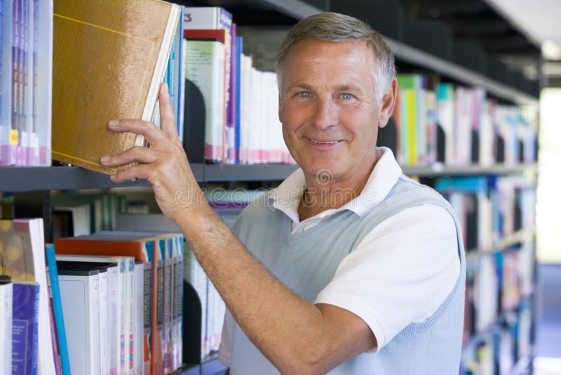 Senior Man Pulling a Library Book Off Shelf Stock Photo - Image of ...