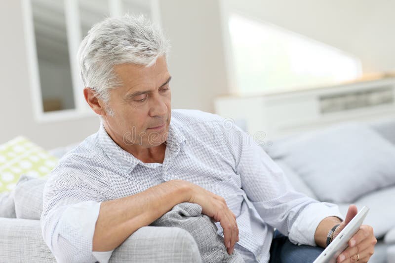 Senior Man Relaxing on Sofa Holding Tablet Stock Photo - Image of ...