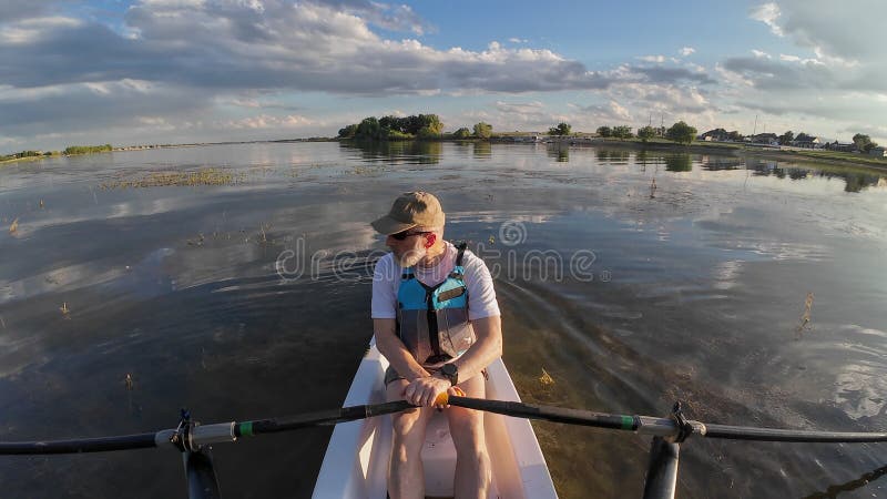 Senior Man in a Rowing Shell is Going Slowly through a Field of Dense ...