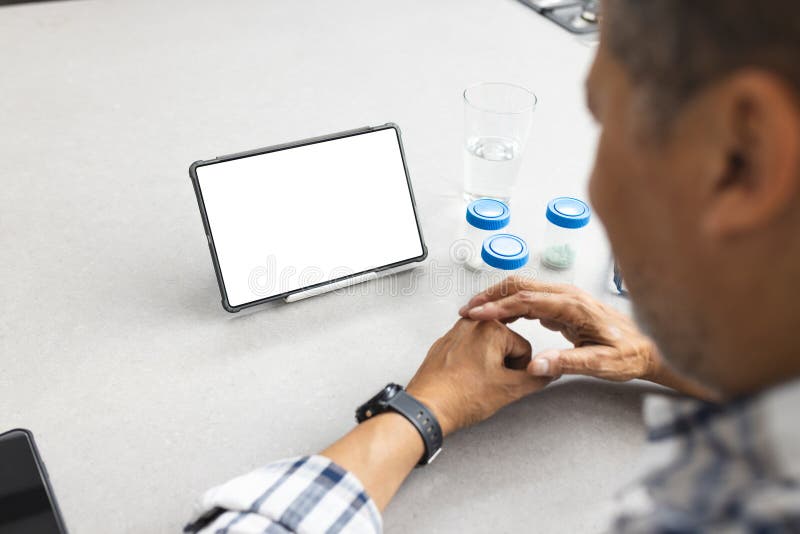 A Senior Man is Seated at a Table with Medication and a Digital Tablet ...