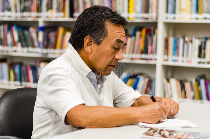 Senior Man Sitting in a Library Writing in a Notepad Stock Image ...