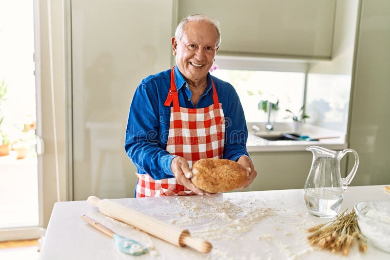 Senior Man Smiling Confident Holding Homemade Bread at Kitchen Stock ...