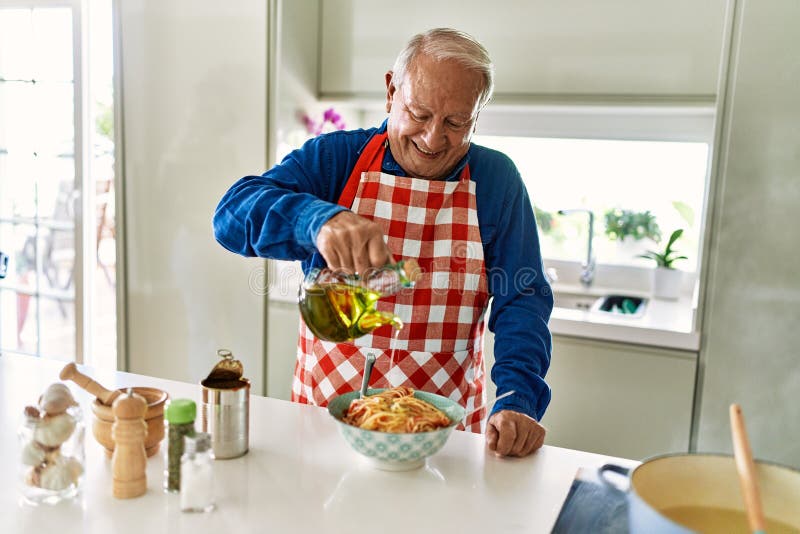 Senior Man Smiling Confident Pouring Oil on Spaghetti at Kitchen Stock ...