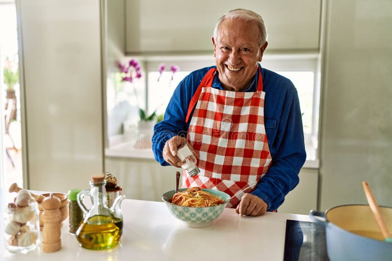 Senior Man Smiling Confident Pouring Salt on Spaghetti at Kitchen Stock ...