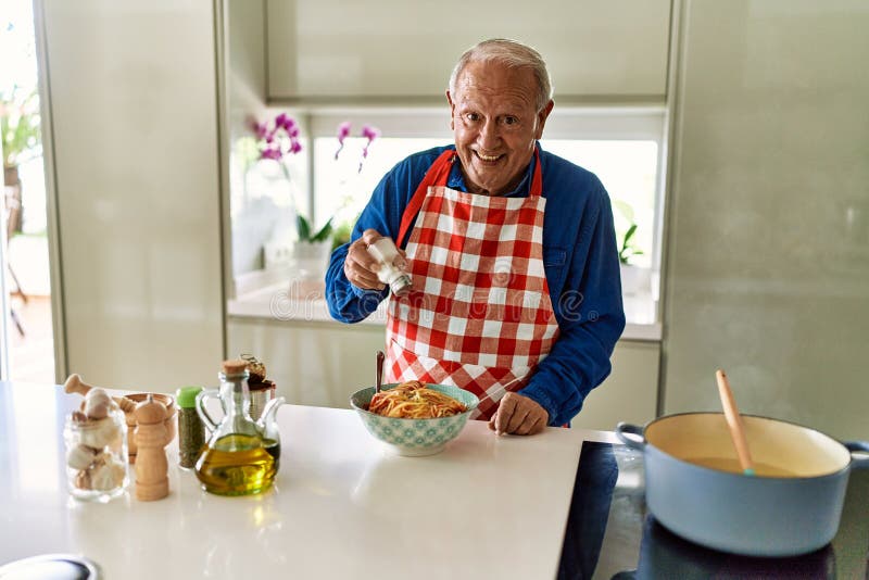 Senior Man Smiling Confident Pouring Salt on Spaghetti at Kitchen Stock ...