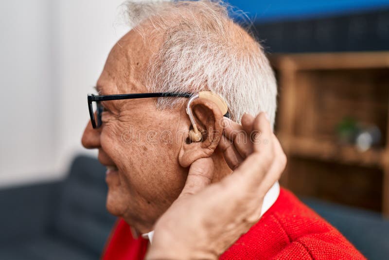 Senior Man Smiling Confident Using Deafness Hearing Aid at Home Stock ...